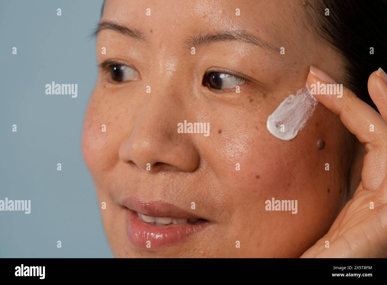 Mid adult woman applying cream Stock Photo - Alamy
