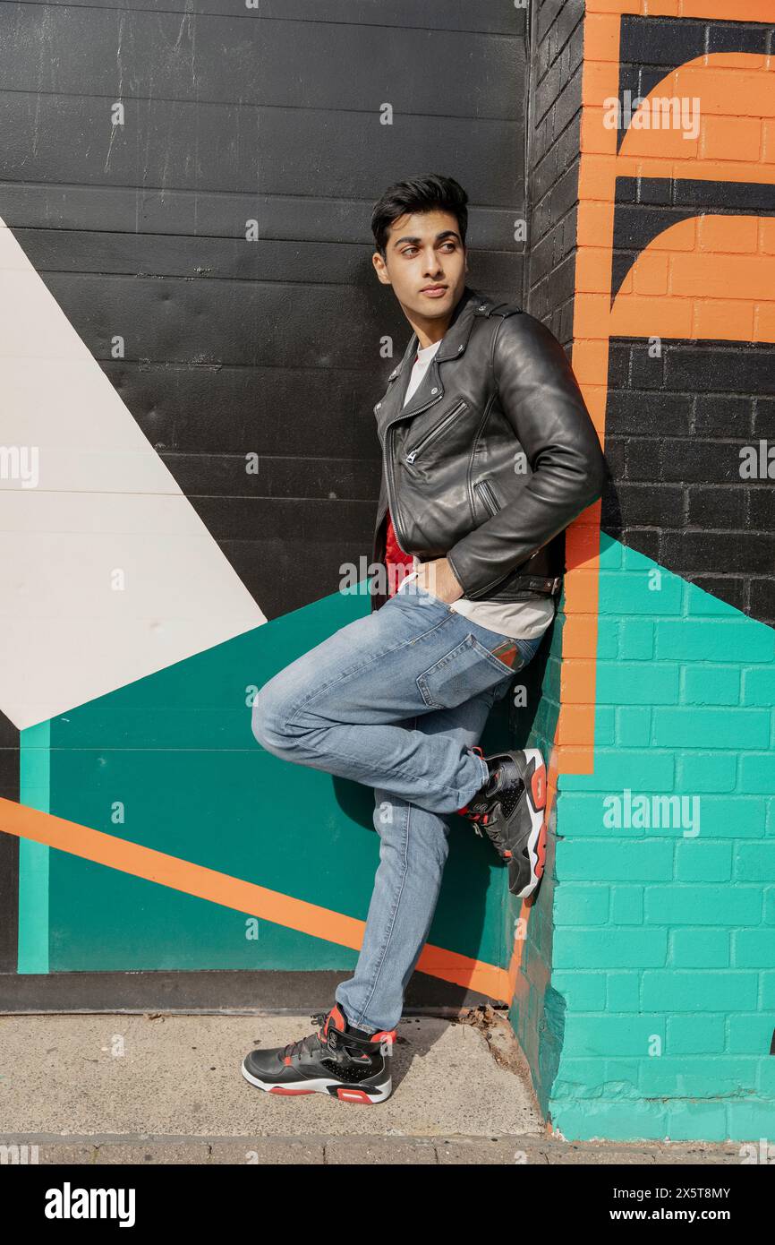 Young man leaning against wall Stock Photo - Alamy