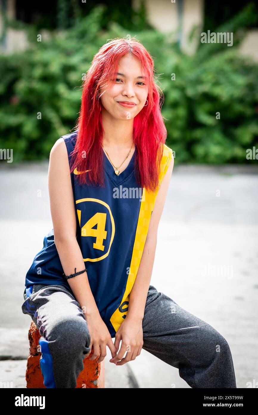 A beautiful young Filipino girl with red hair poses outside her home in ...