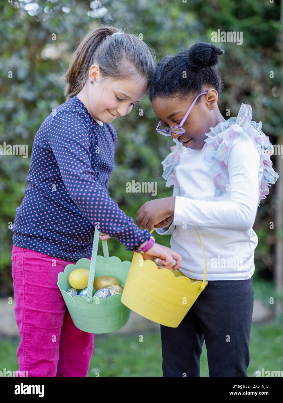 Girl friends (6-7) with baskets on Easter egg hunt Stock Photo - Alamy