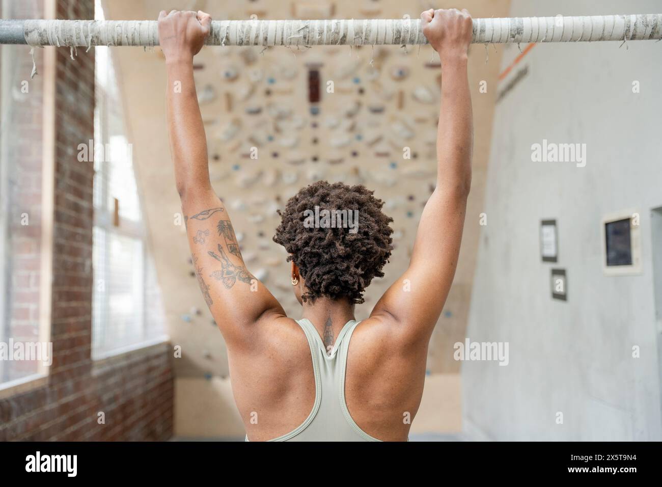 Woman performing chin-up exercise next to climbing wall Stock Photo - Alamy