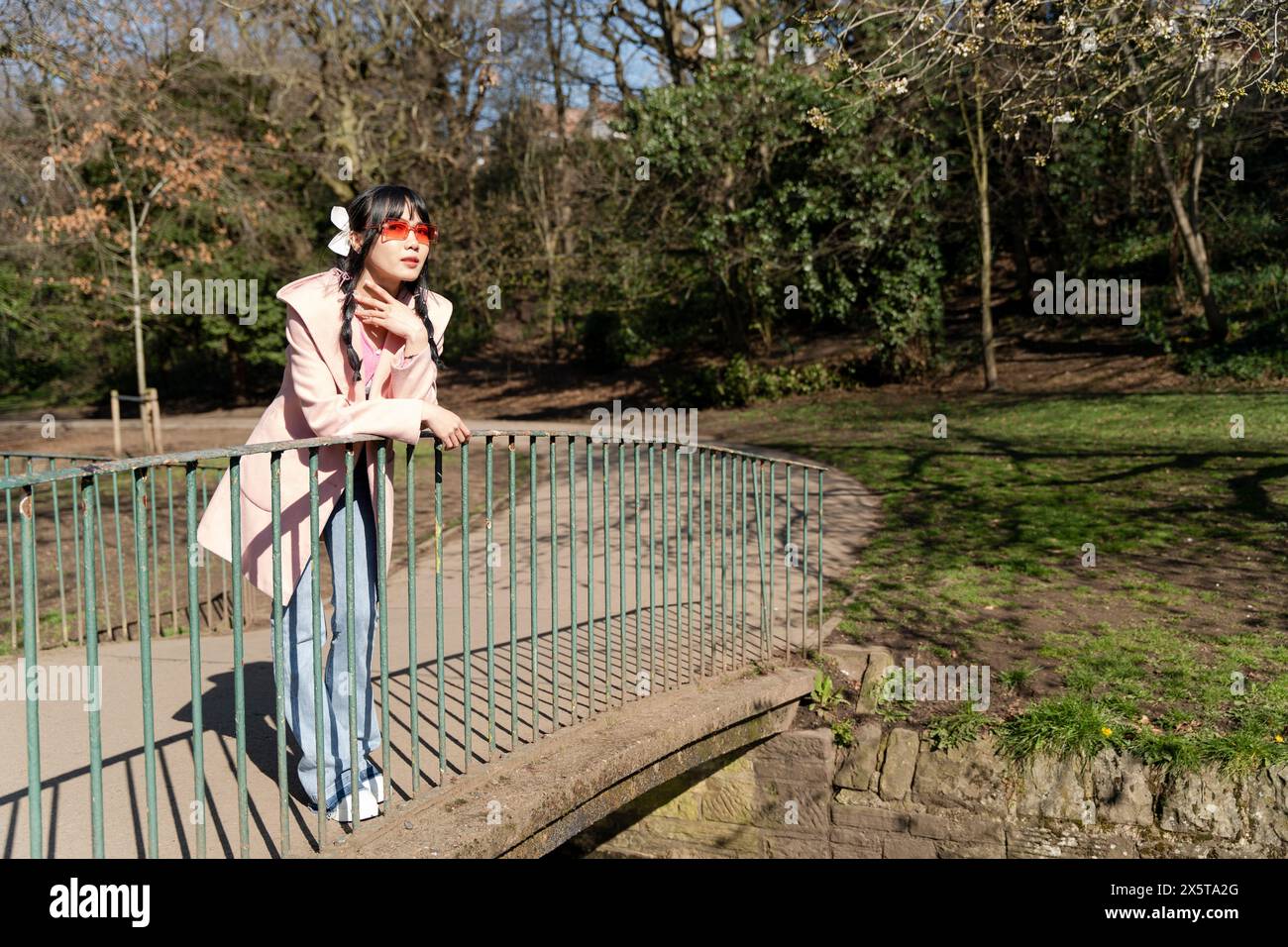 Young woman standing on bridge in park Stock Photo - Alamy