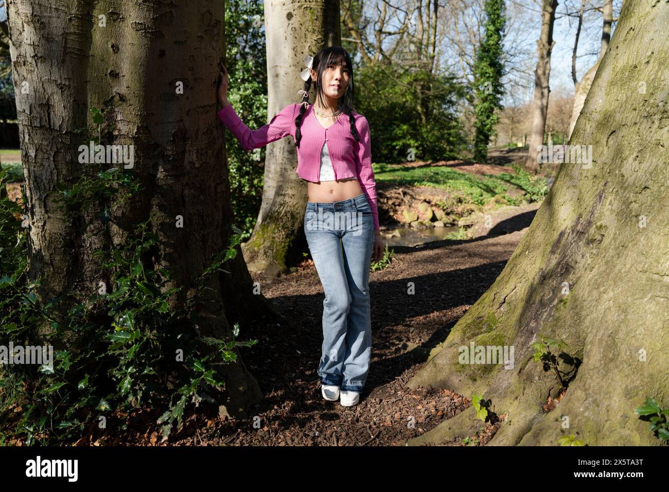 Young woman leaning against a tree in a park hi-res stock photography ...