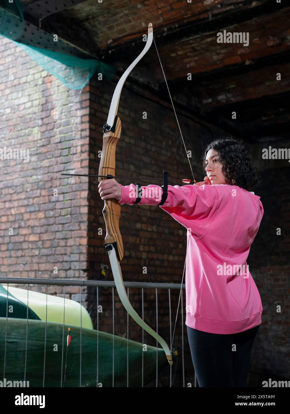 Young woman aiming with bow during training Stock Photo - Alamy