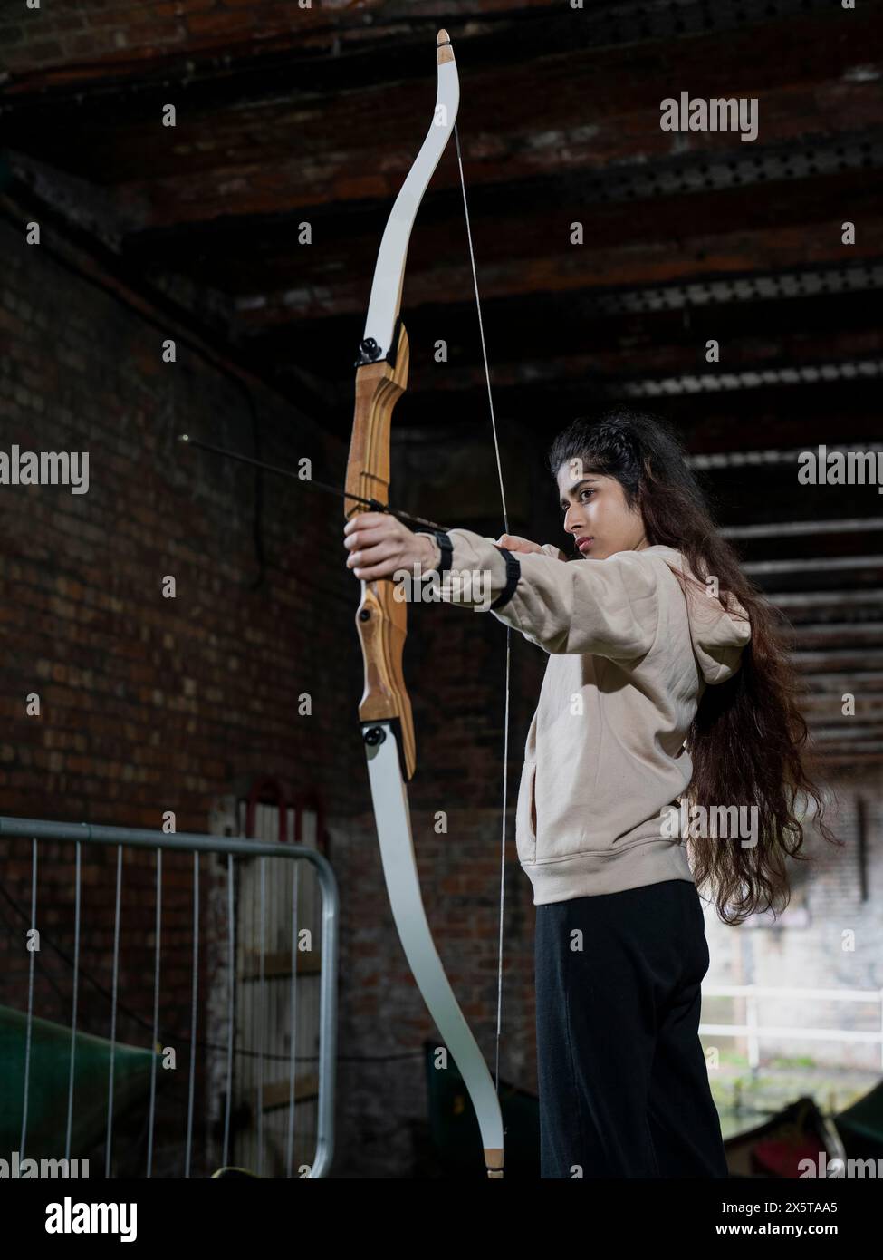 Young woman aiming with bow during archery training Stock Photo - Alamy
