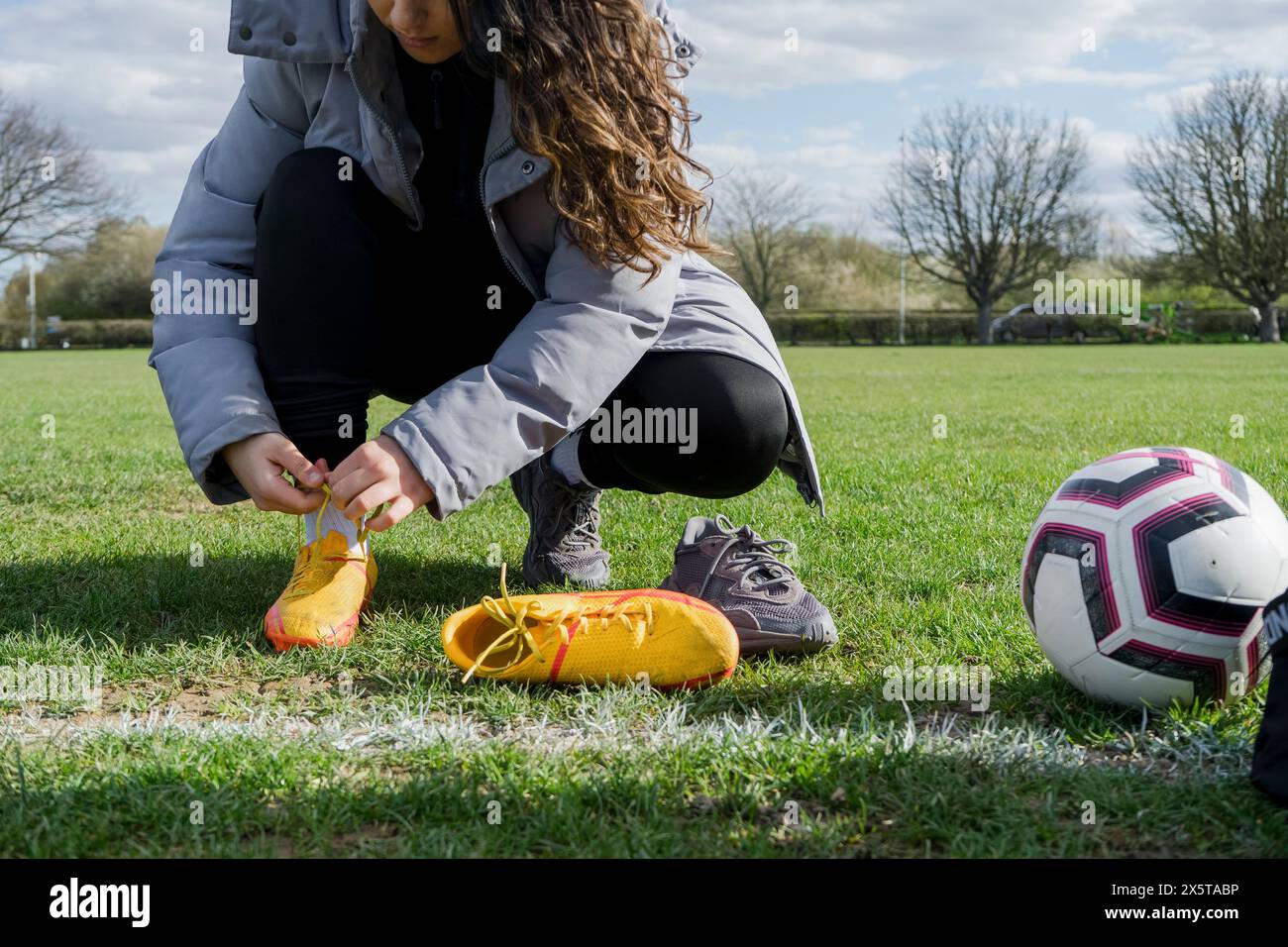 Young woman putting on football cleats Stock Photo - Alamy