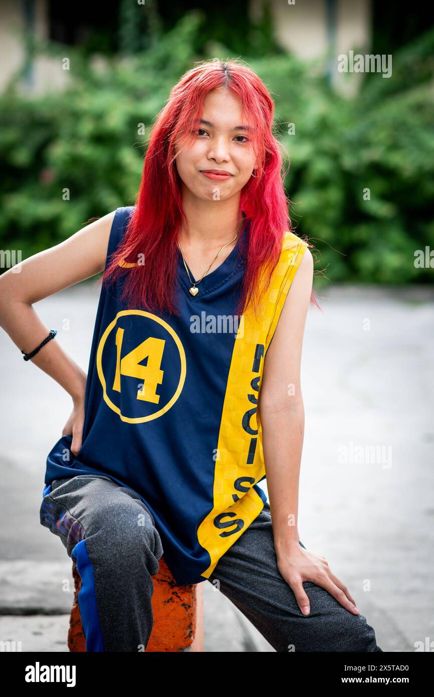 A beautiful young Filipino girl with red hair poses outside her home in ...