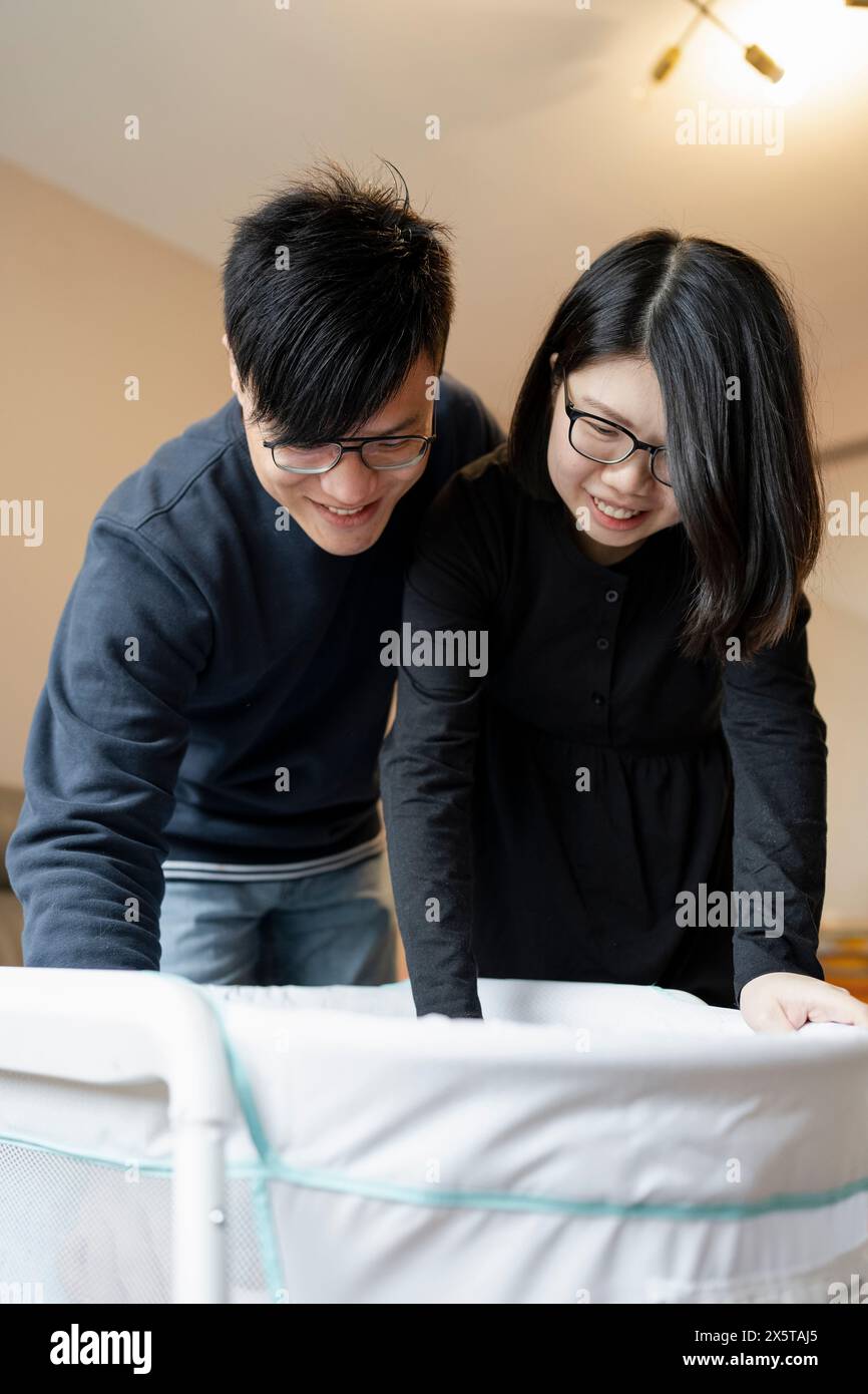 Parents looking into baby crib Stock Photo - Alamy