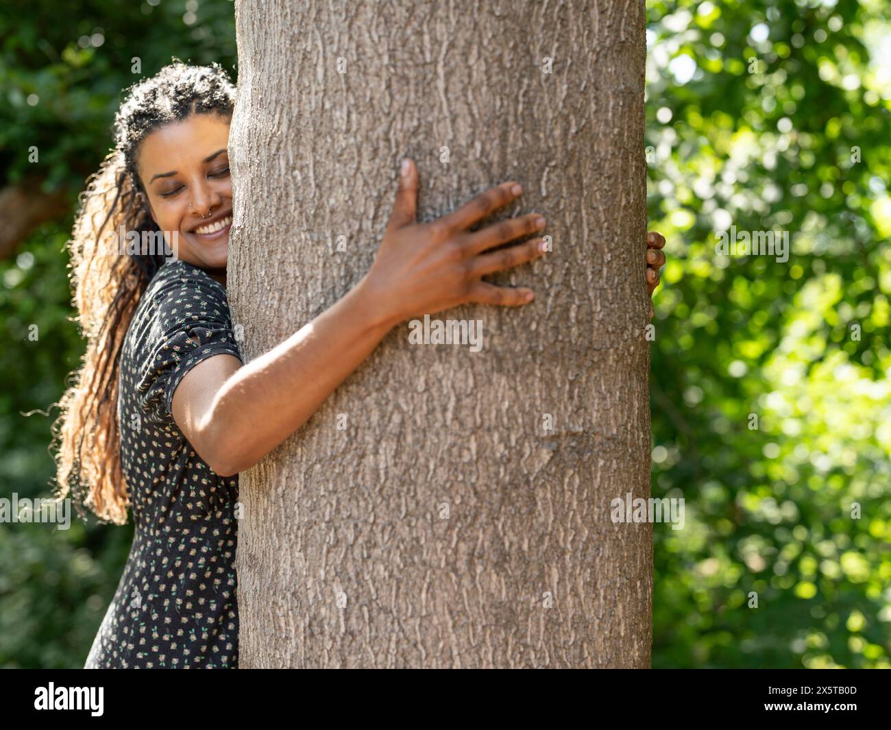 Portrait of smiling woman hugging tree Stock Photo - Alamy