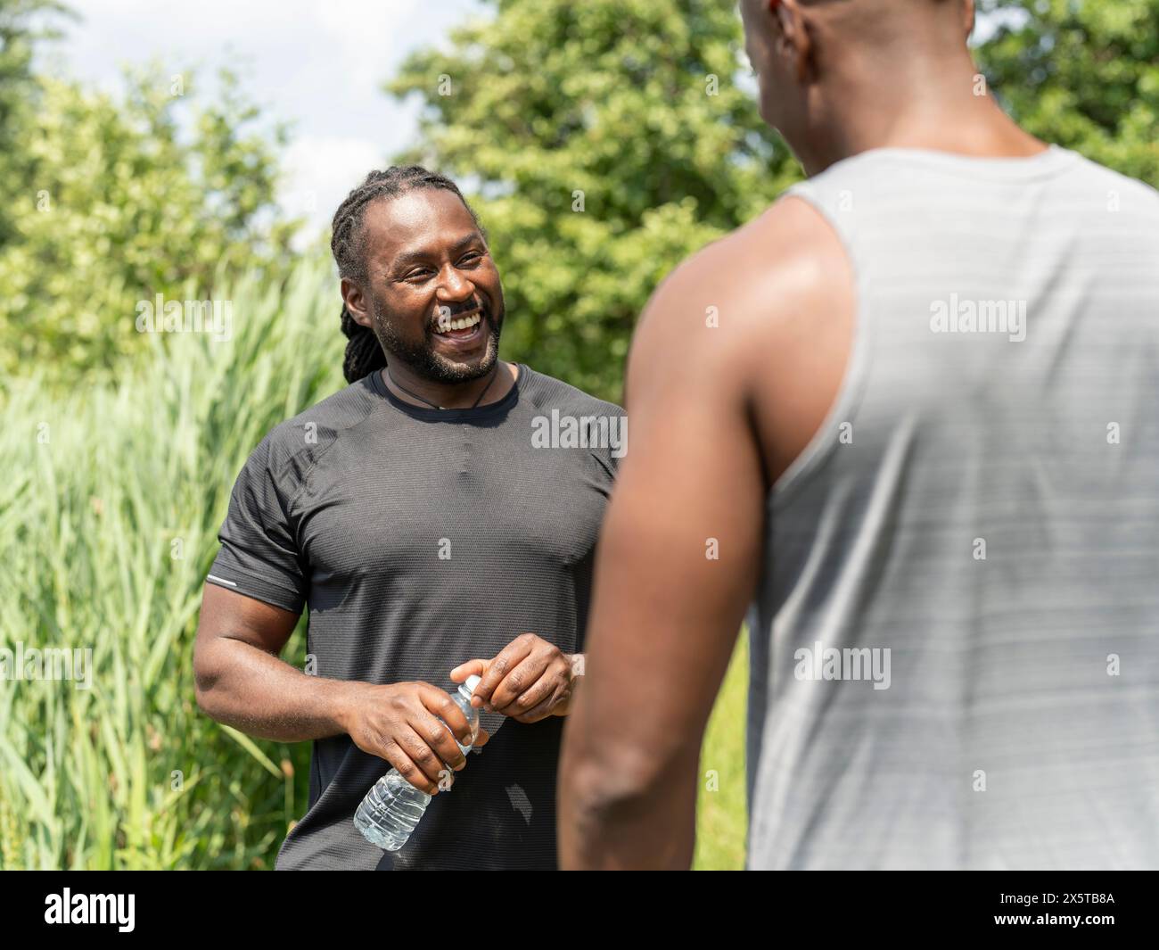 Two men drinking water after exercising outdoors Stock Photo - Alamy