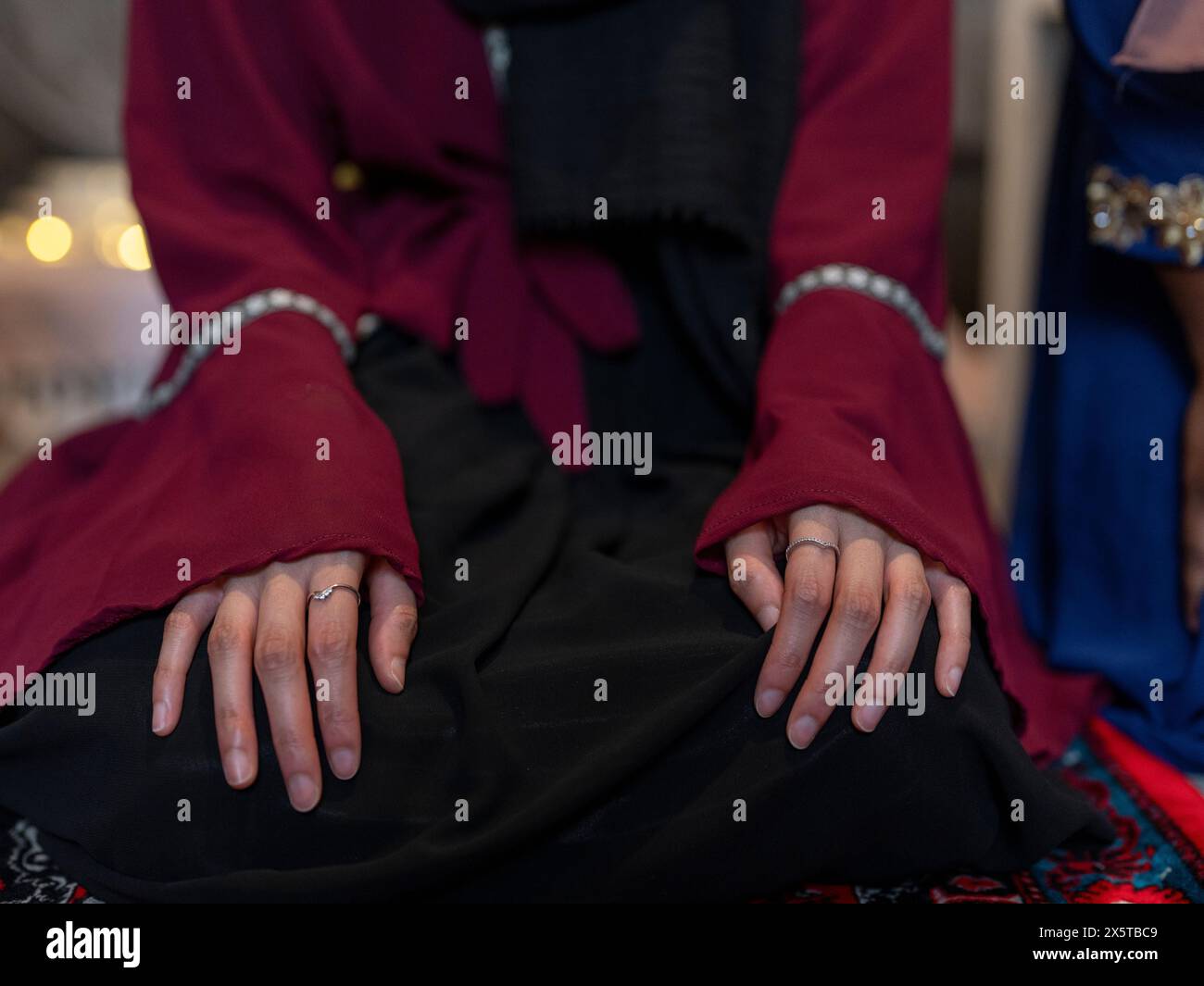 Kneeling woman holding hands on knees during Ramadan prayer at home ...