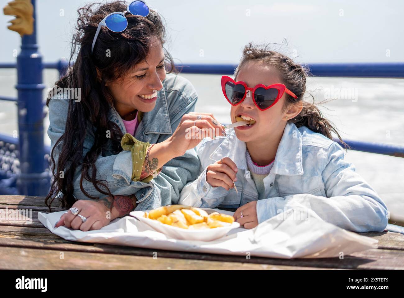 Mother and daughter (8-9) eating fish and chips at seaside Stock Photo ...