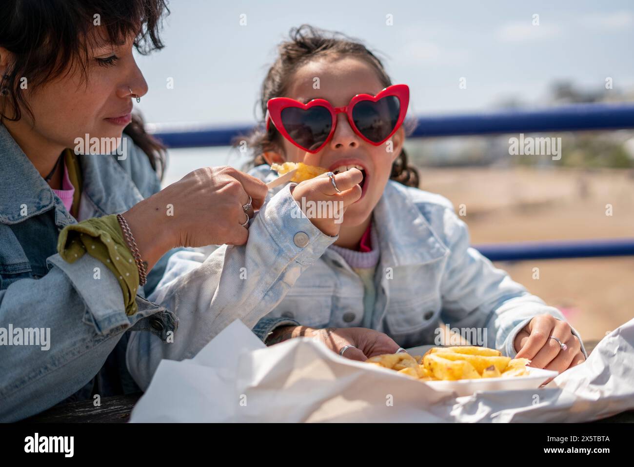 Mother and daughter (8-9) eating fish and chips at seaside Stock Photo ...