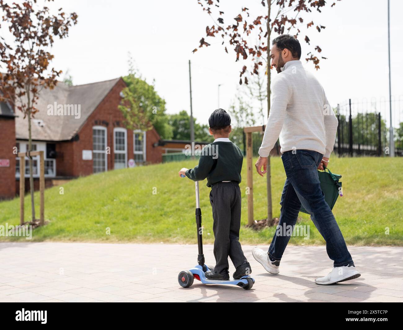 Boy (6-7) on push scooter walking with father to school Stock Photo - Alamy