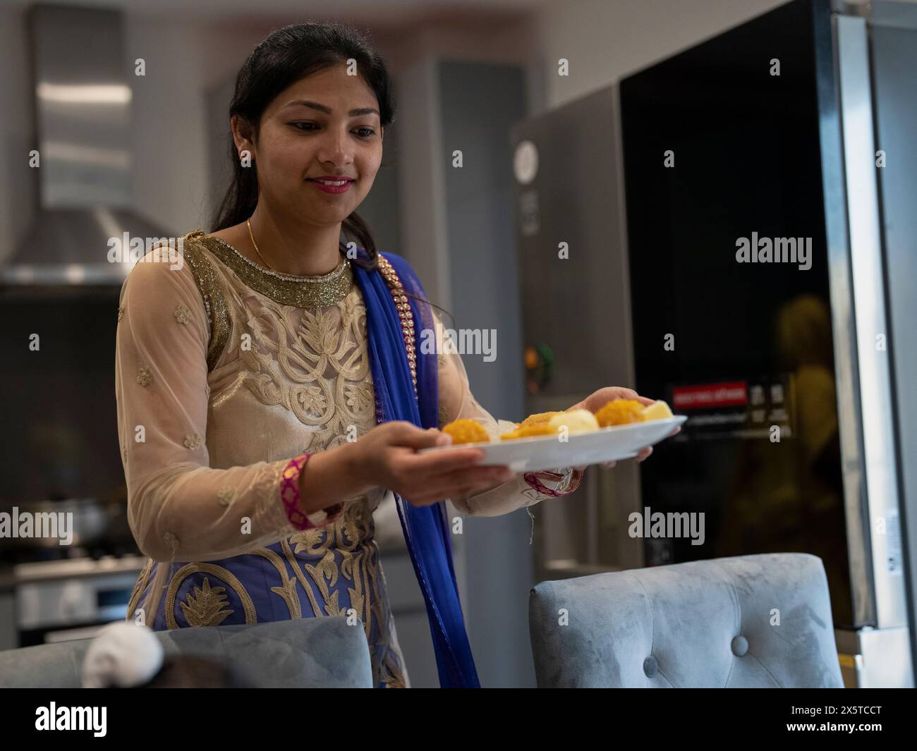 Young woman in traditional clothing carrying food on plate Stock Photo ...