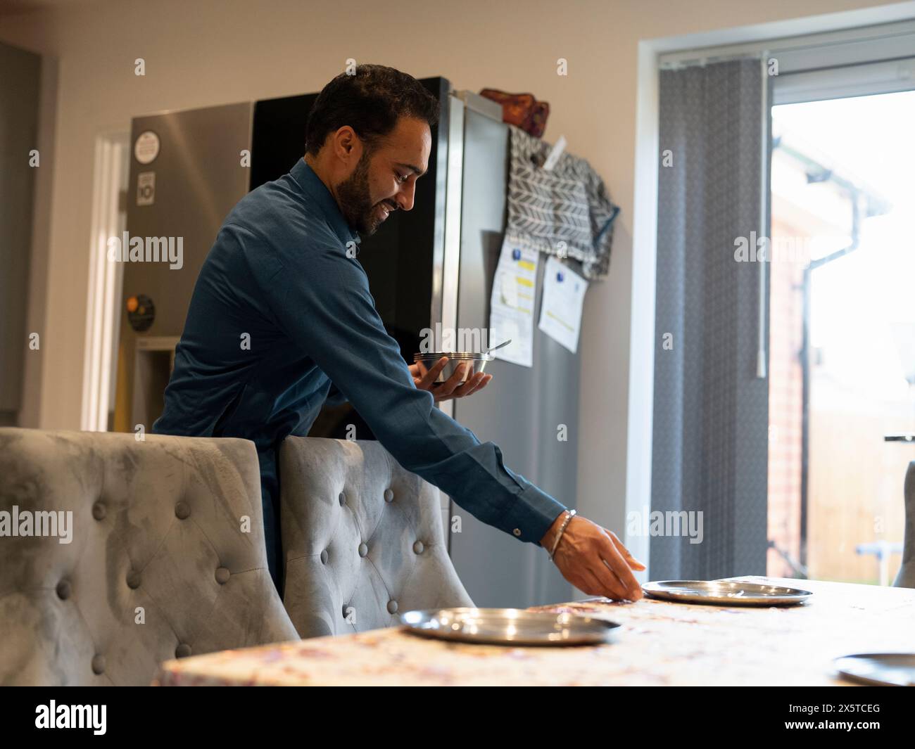 Smiling man setting table at home Stock Photo - Alamy