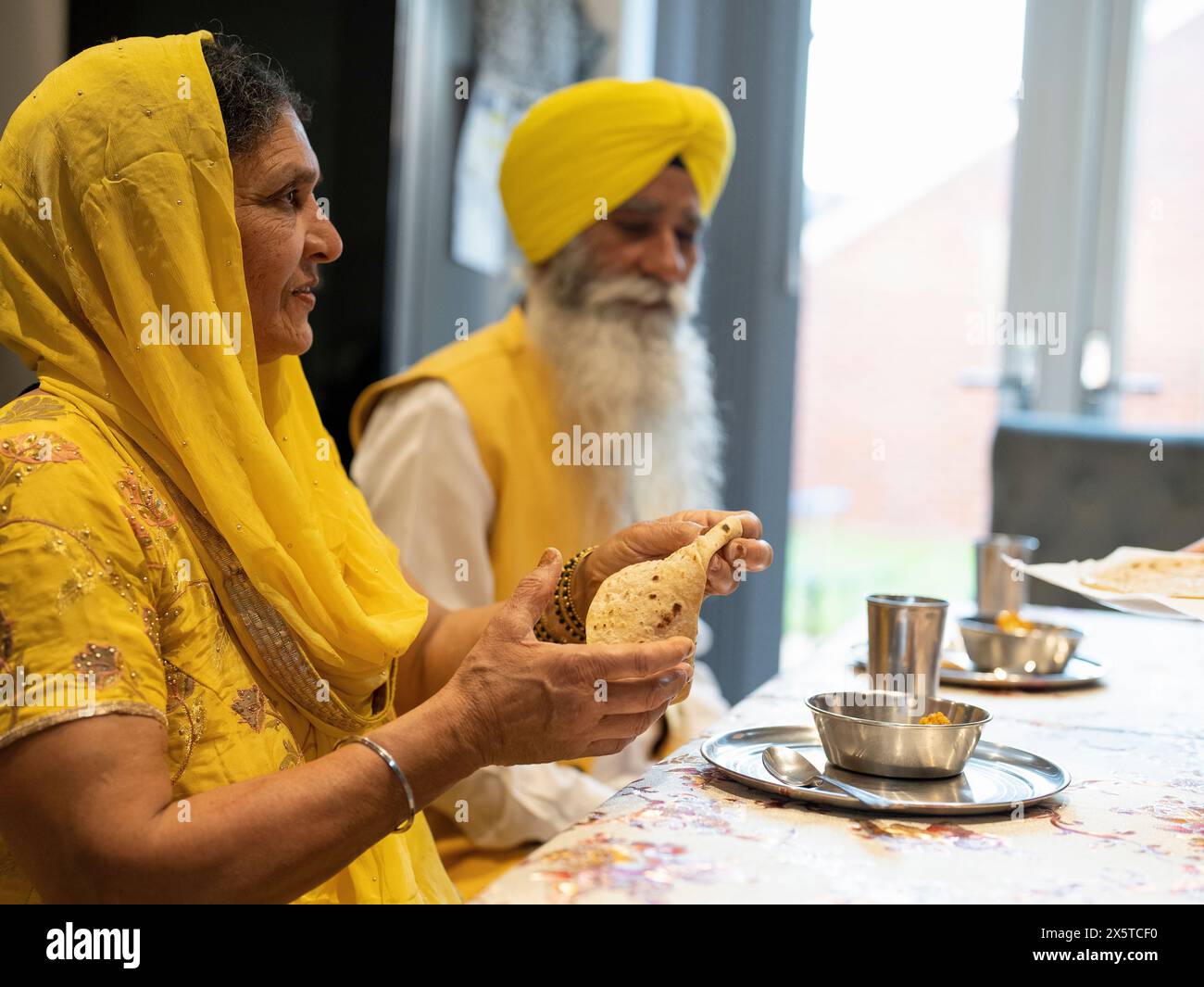 Couple in traditional clothing eating meal at home Stock Photo - Alamy