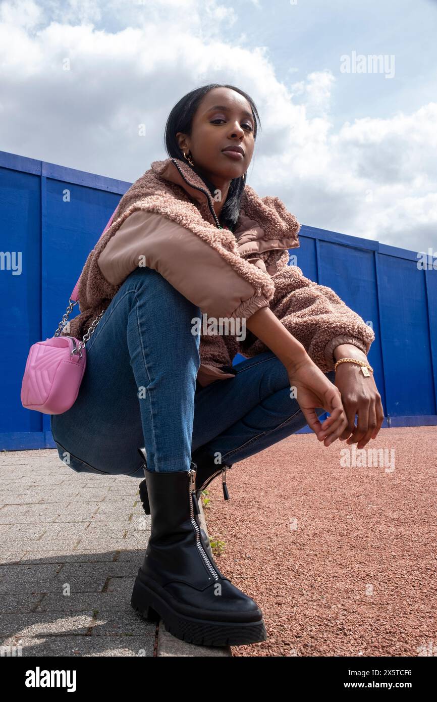 Portrait of young woman crouching outdoors Stock Photo - Alamy