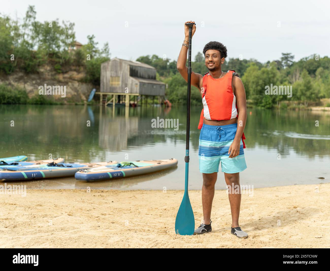 Portrait of young man standing with oar on beach Stock Photo - Alamy