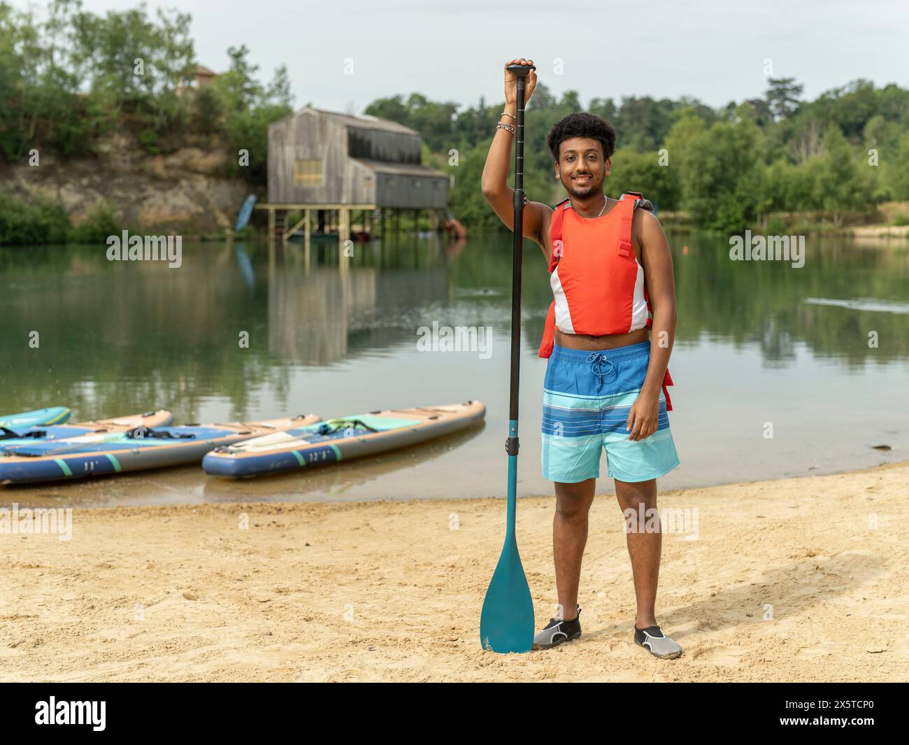 Portrait of young man standing with oar on beach Stock Photo - Alamy
