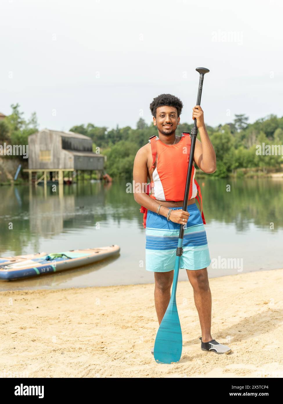 Portrait of young man standing with oar on beach Stock Photo - Alamy
