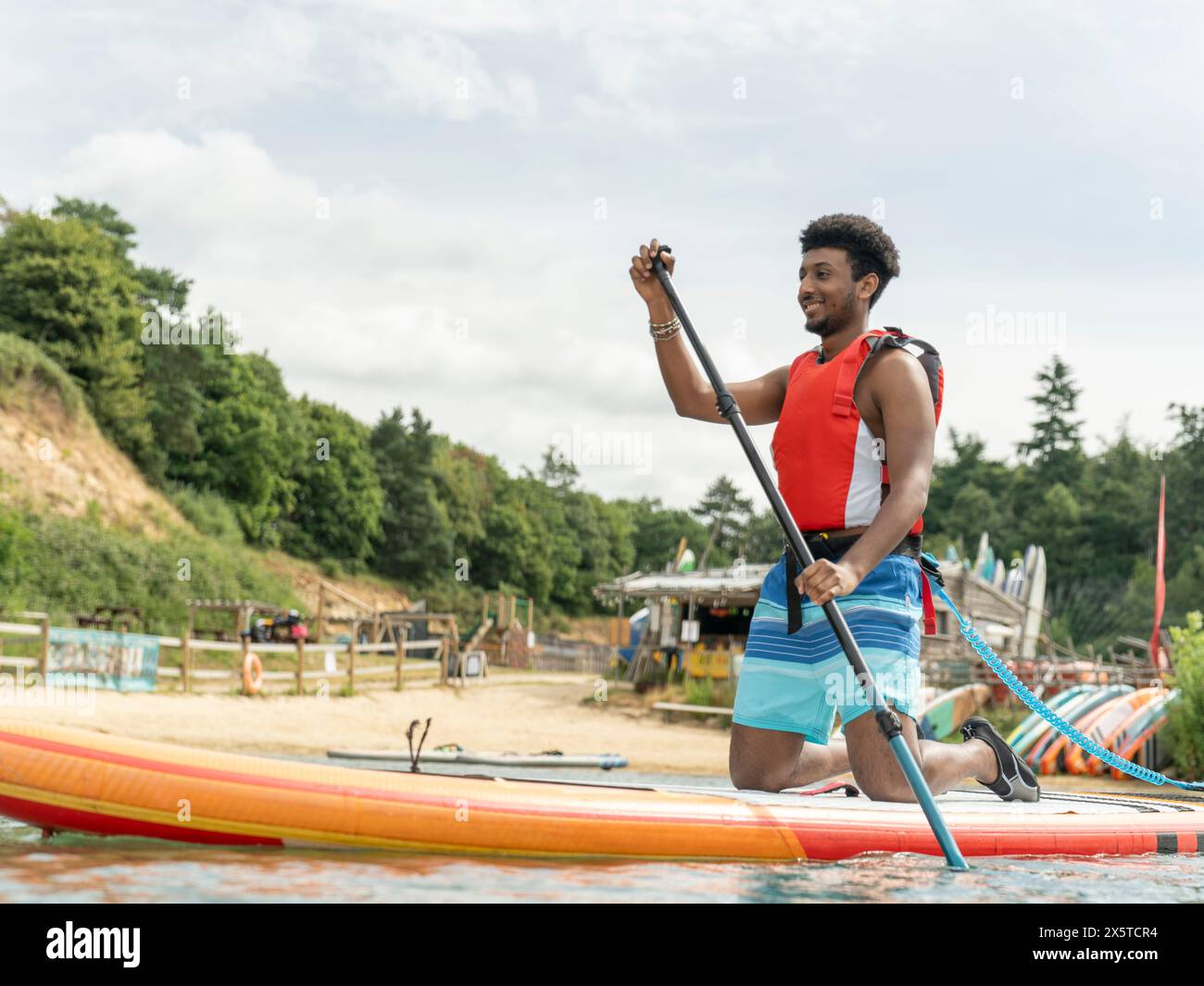 Young man paddleboarding with oar on lake Stock Photo - Alamy