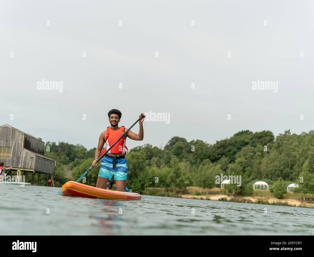 Young man paddleboarding on lake Stock Photo - Alamy