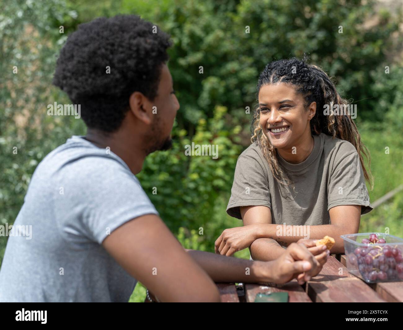 Friends eating snacks by picnic table Stock Photo - Alamy