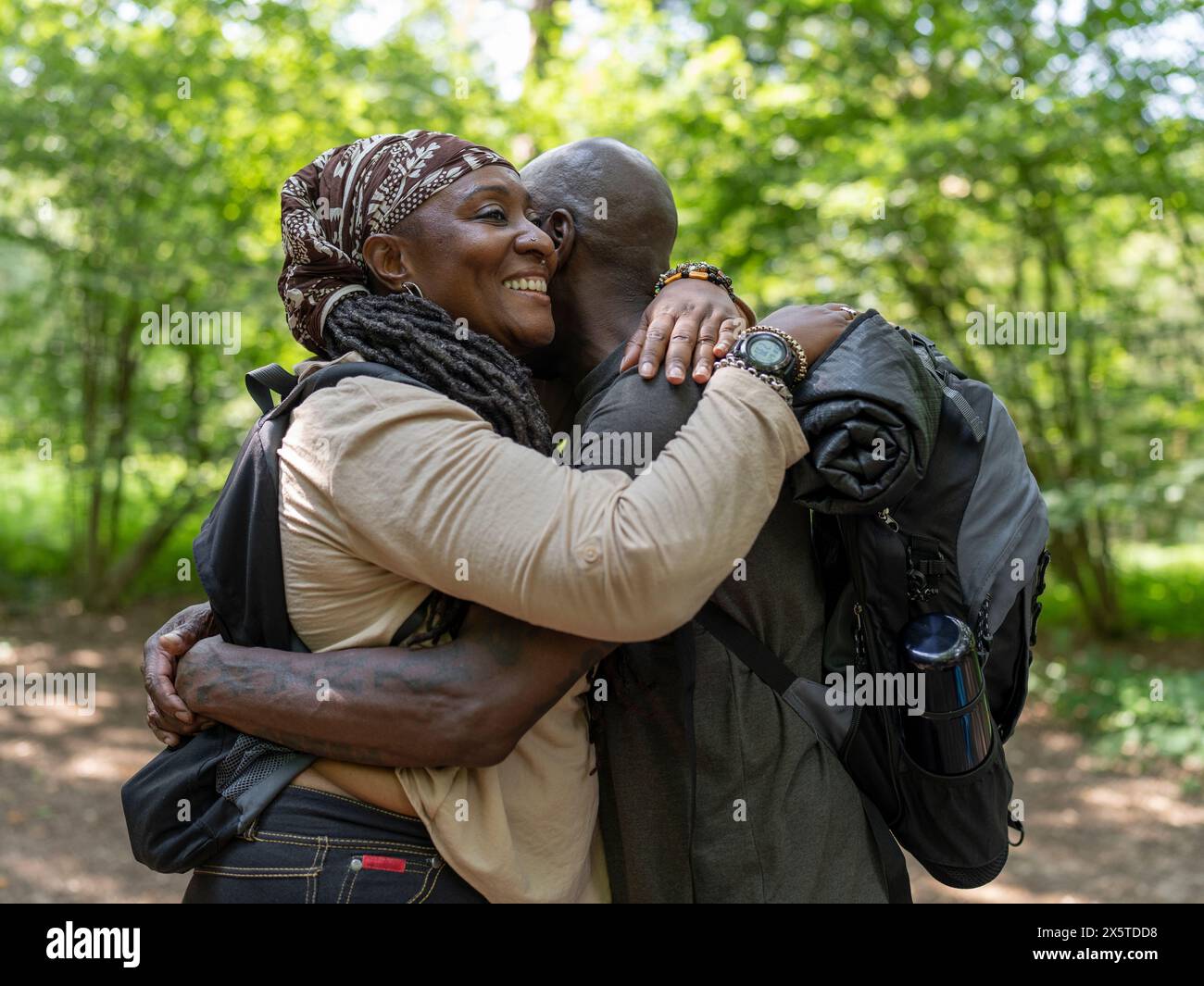 Smiling hiking couple hugging in forest Stock Photo - Alamy