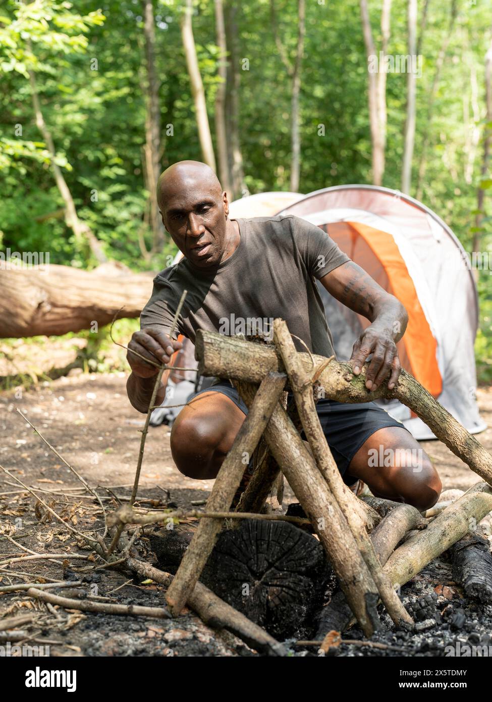 Mature man making fire in forest Stock Photo - Alamy