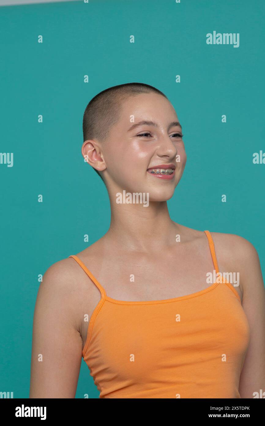 Studio portrait of smiling girl in orange top Stock Photo - Alamy
