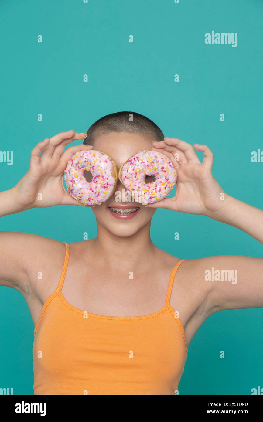 Studio portrait of smiling girl holding donuts in front of face Stock ...