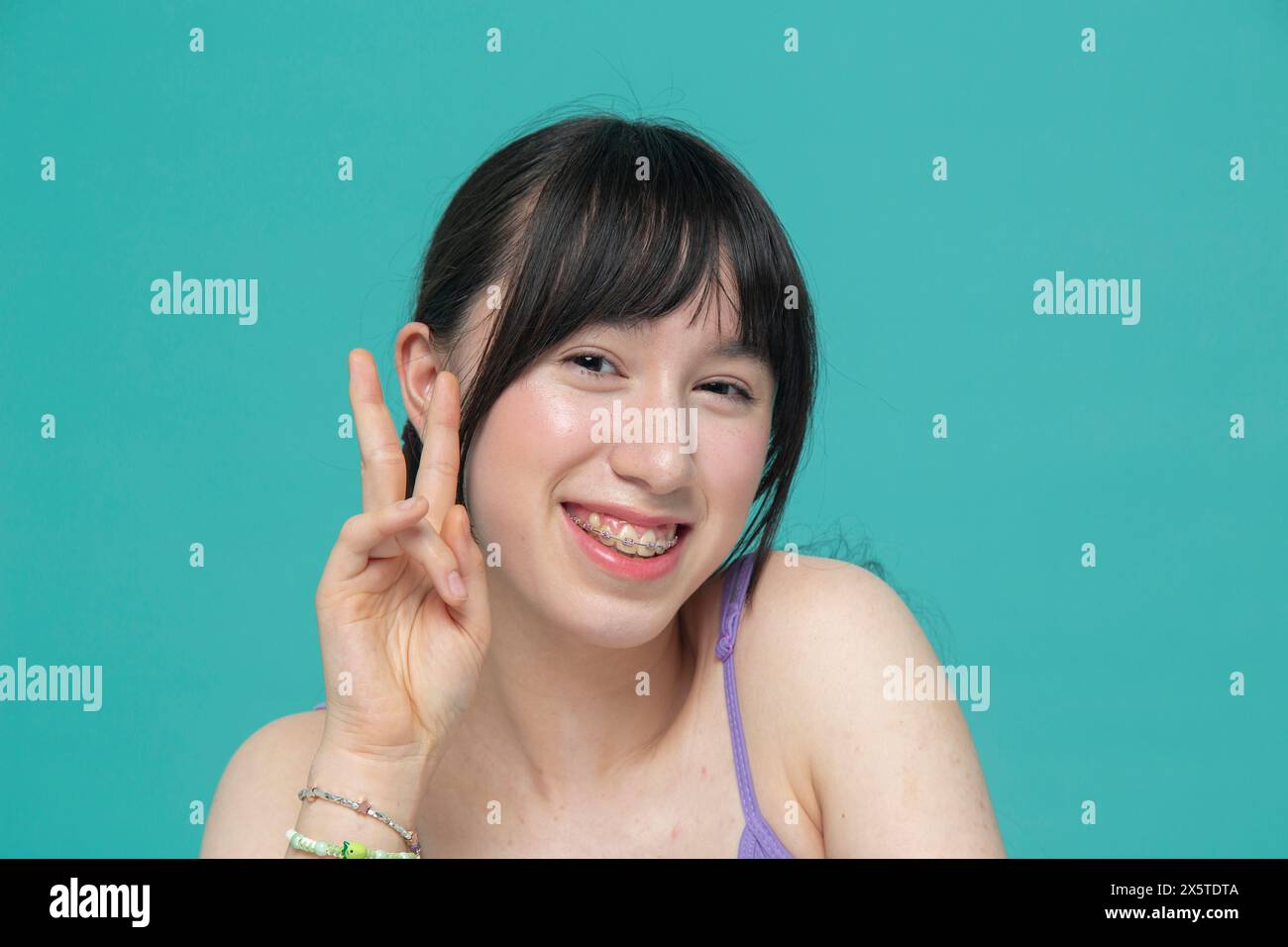Studio portrait of smiling girl showing peace sign Stock Photo - Alamy