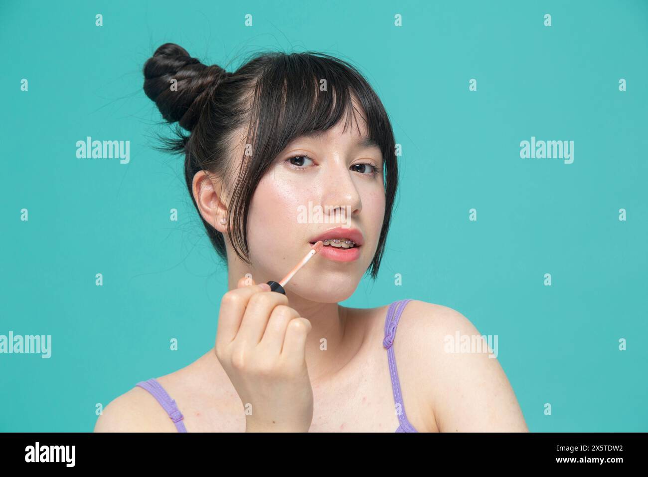 Studio portrait of girl applying lip gloss Stock Photo - Alamy