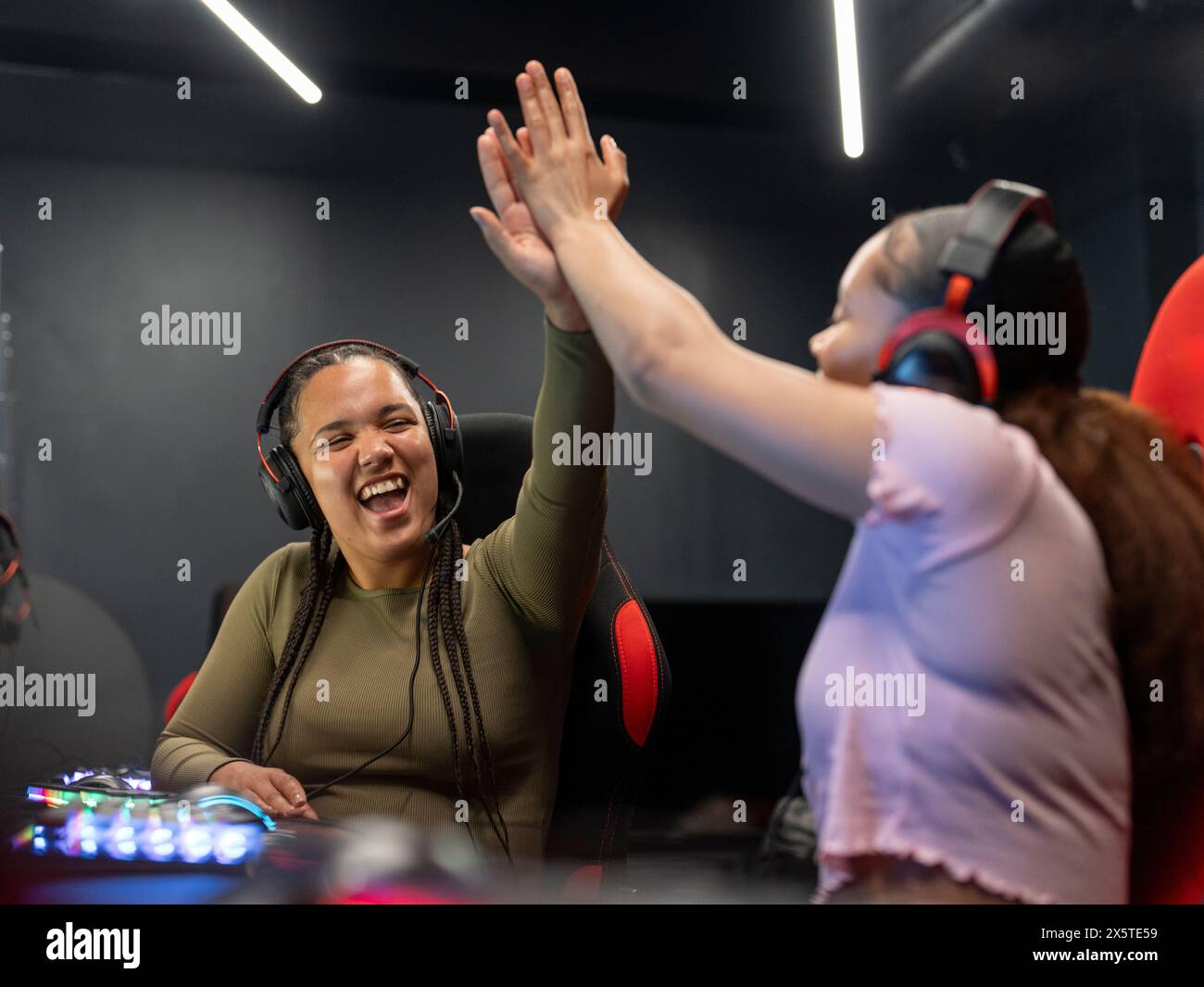 Female gamers giving high-five while playing video games Stock Photo ...