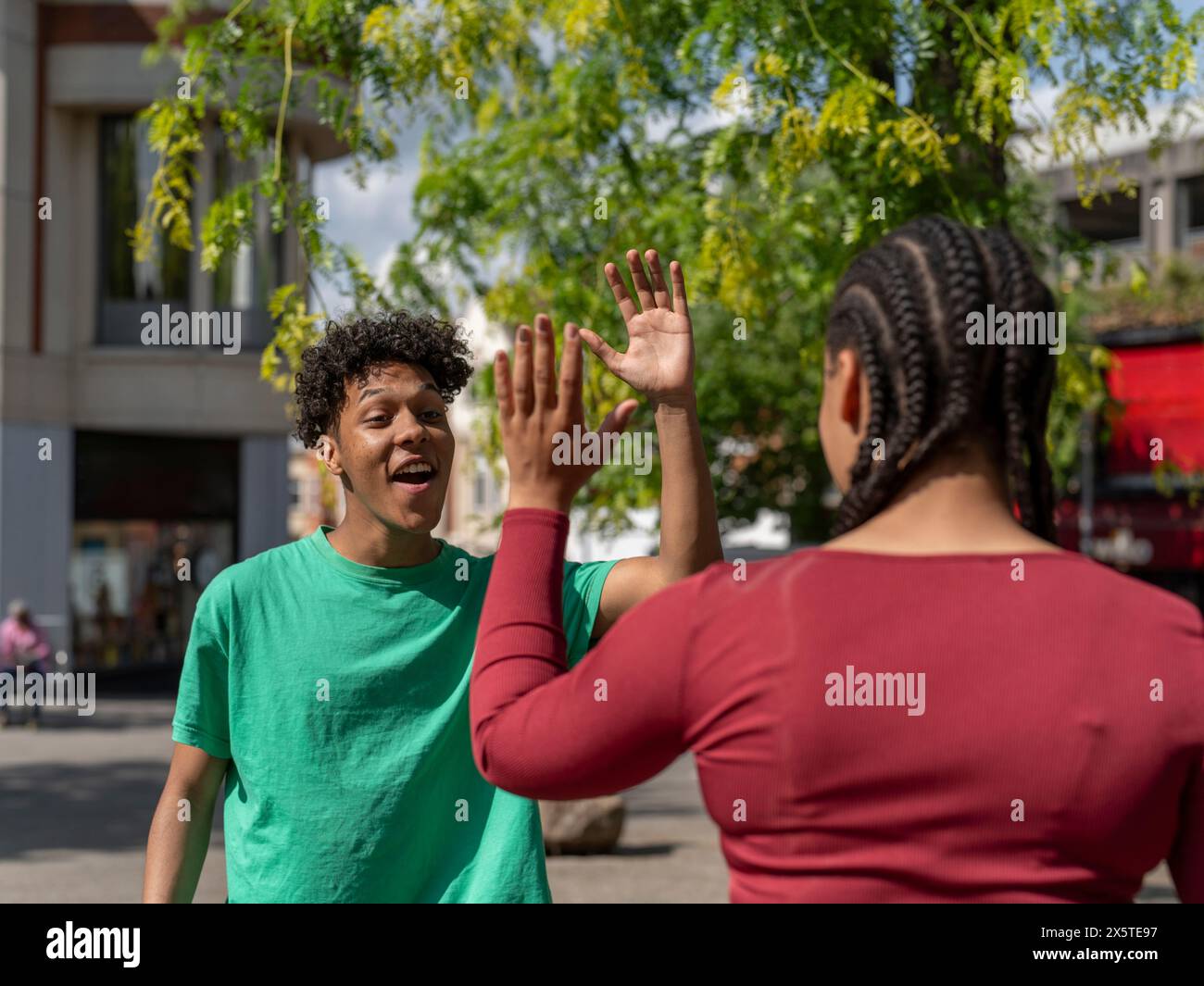 Two friends giving high-five in city street Stock Photo - Alamy