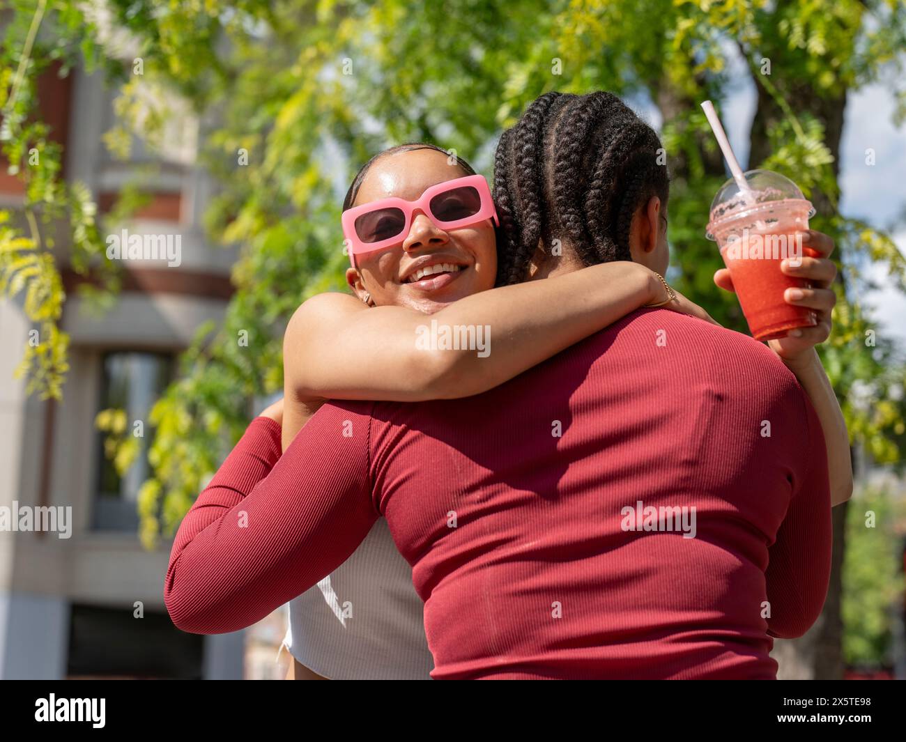 Two female friends embracing on sunny day Stock Photo - Alamy