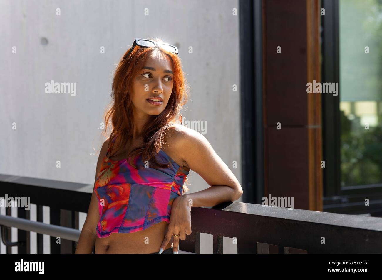 Young woman leaning against railing Stock Photo - Alamy