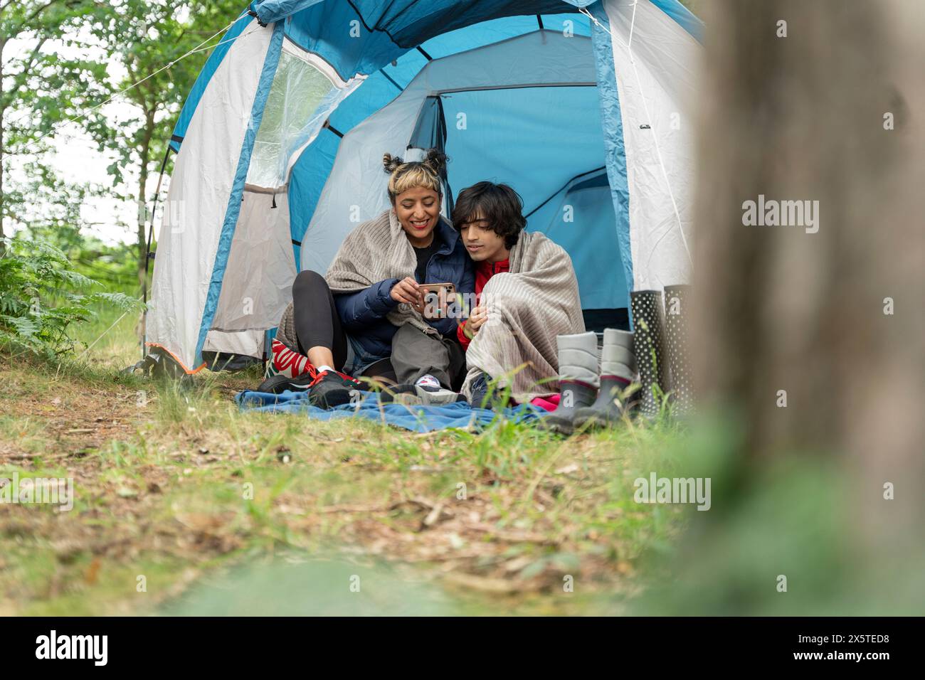Mother and son using phone in tent Stock Photo - Alamy