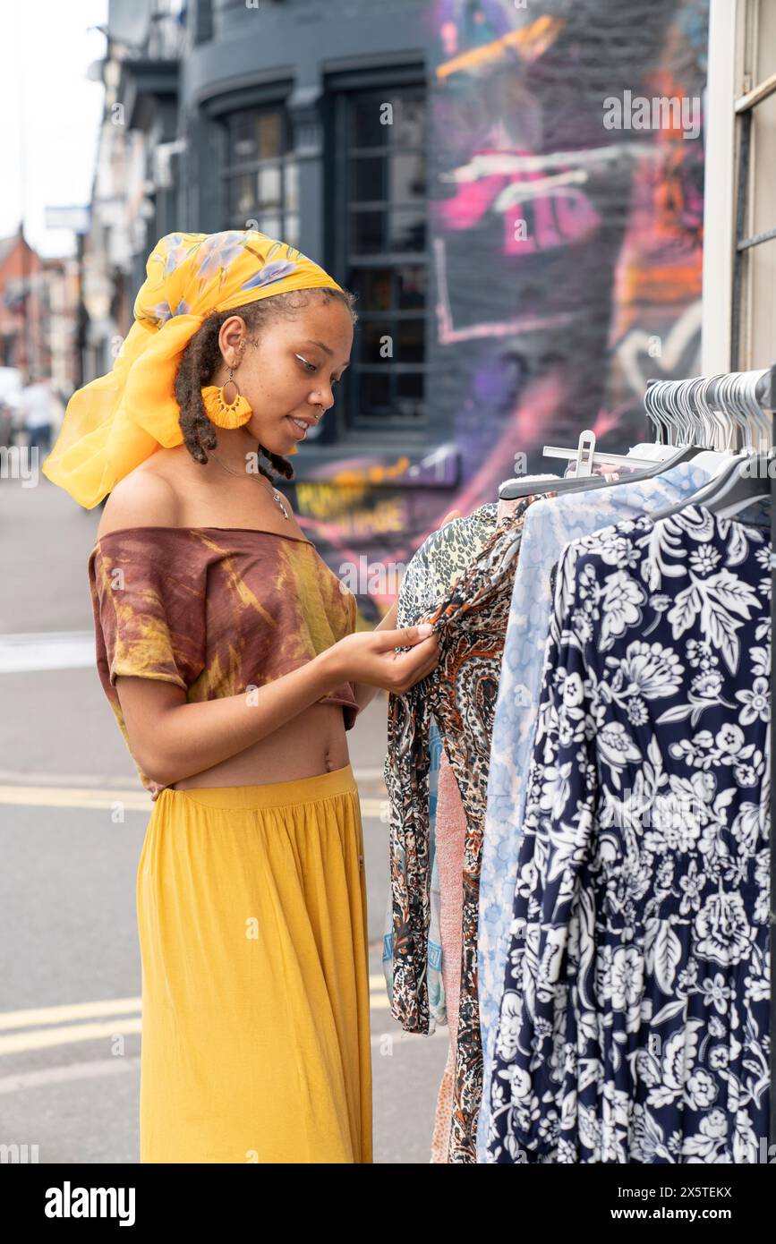 Young woman looking at clothes rack in outdoor display Stock Photo - Alamy
