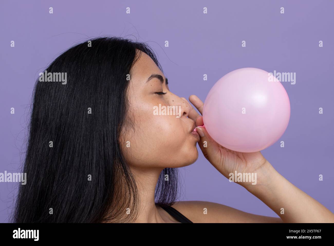 Woman blowing pink balloon hi-res stock photography and images - Alamy