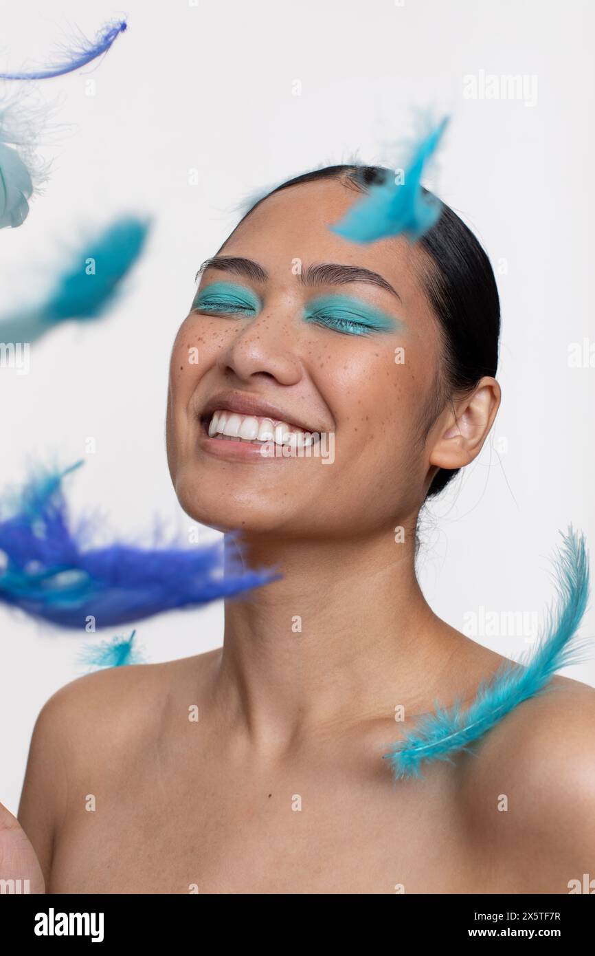 Blue feathers falling in front of smiling woman with closed eyes Stock ...