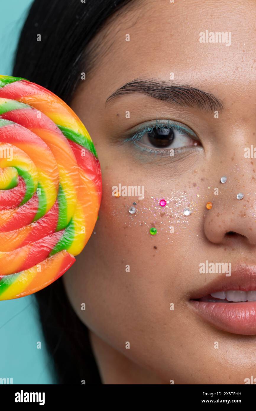 Woman holding colorful lollipop in front of face Stock Photo - Alamy