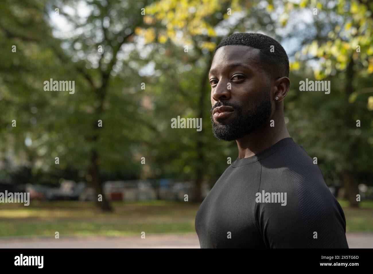 Portrait of athletic man standing in park Stock Photo - Alamy