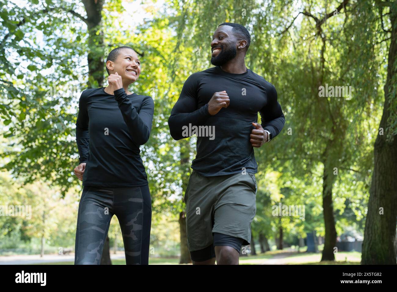 Smiling man and woman jogging in park Stock Photo - Alamy