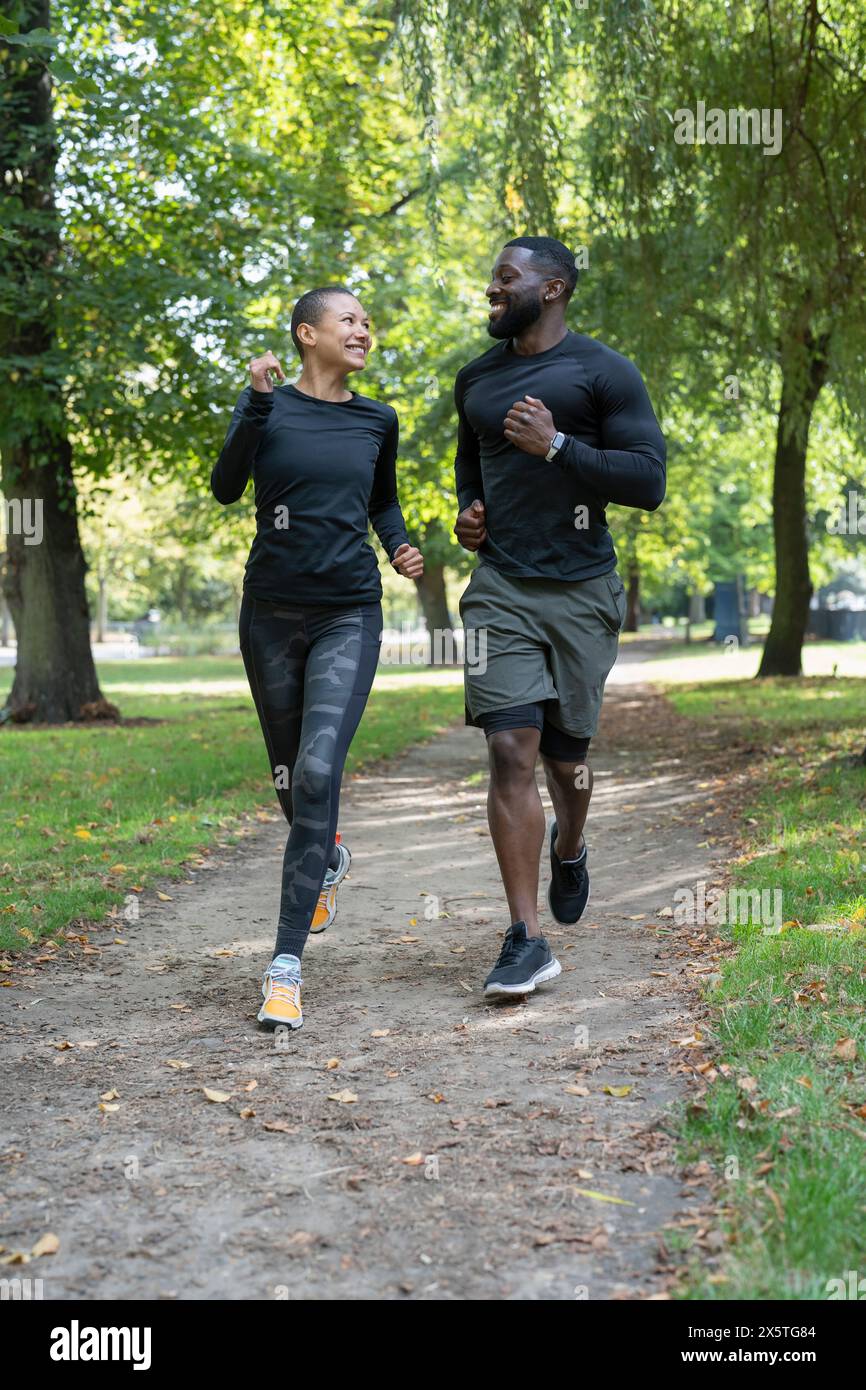 Smiling man and woman jogging in park Stock Photo - Alamy
