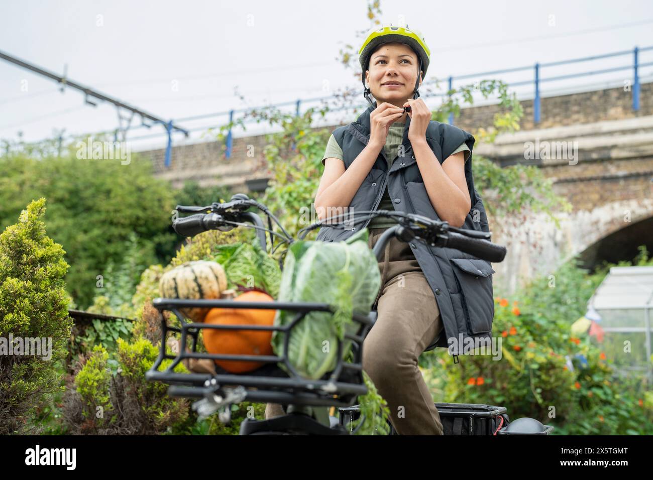 Smiling woman fastening helmet on cargo electric trike with homegrown ...