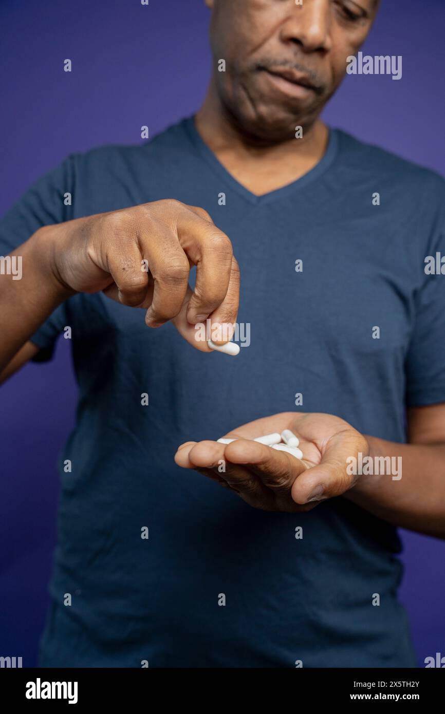 Man taking medicine against purple background Stock Photo - Alamy
