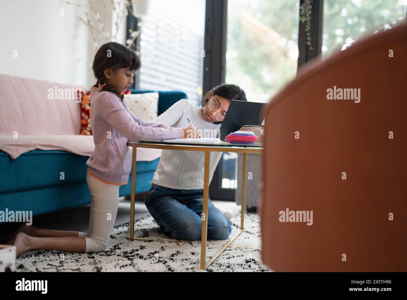 Two sisters doing homework in living room Stock Photo - Alamy