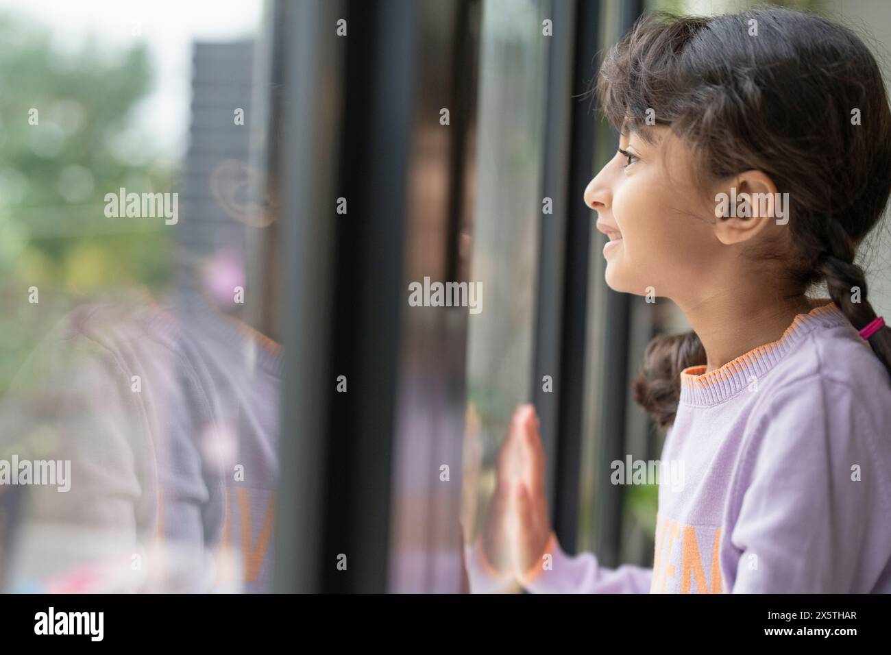 Little girl looking out window Stock Photo - Alamy